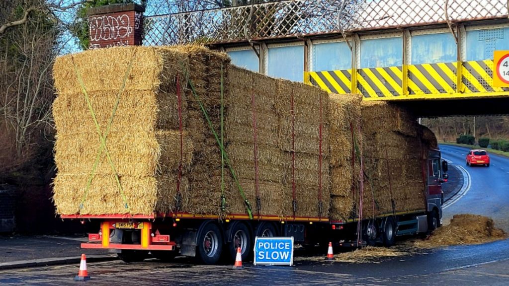 Lorry carrying bales of hay becomes stuck under railway bridge in ...